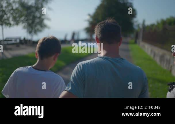 Father and son walking together outside dad putting arm around child ...