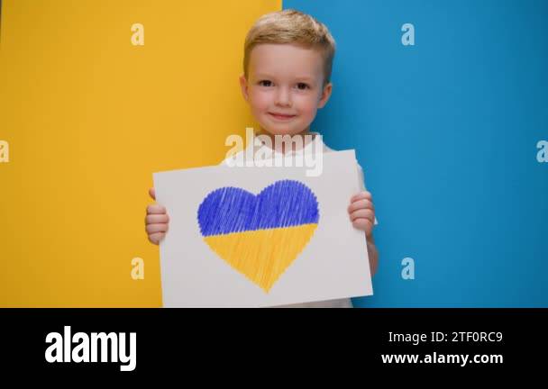 Blond boy smiles holding banner with yellow-blue heart drawn with ...