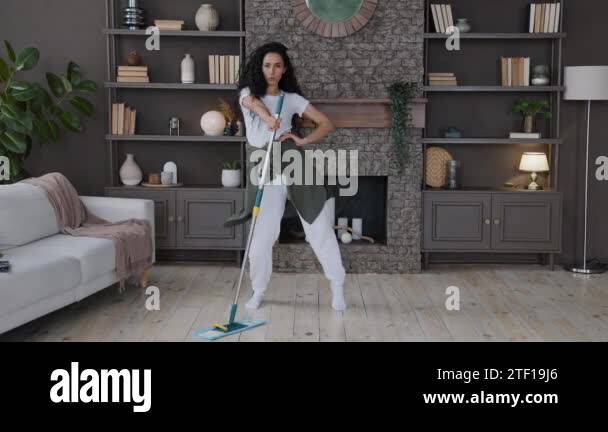 Energetic hispanic woman housewife cleans living room sings song using ...
