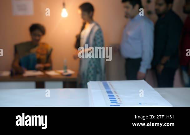 A middle-aged lady officer checking the identity proof of the voters in ...