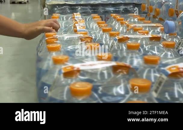 Bottles of water in large packs in a supermarket on a shelf. Guy ...