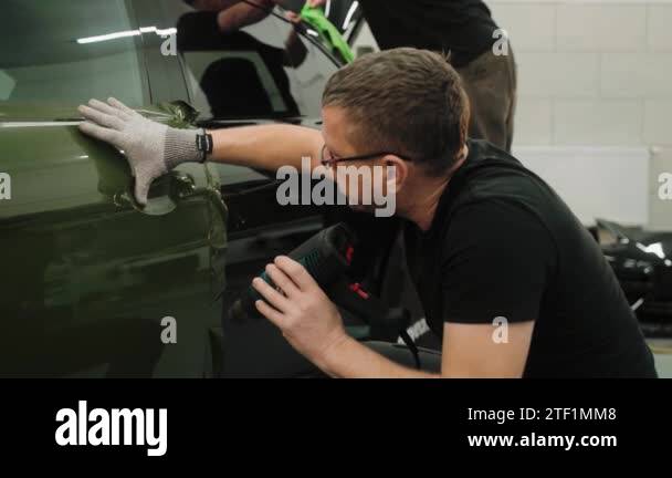 Close up shot of man vinyl wrapping the car door, smoothing the film ...