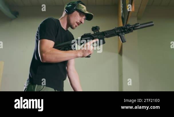 A man wearing goggles and ear protection unloads a long gun by removing ...