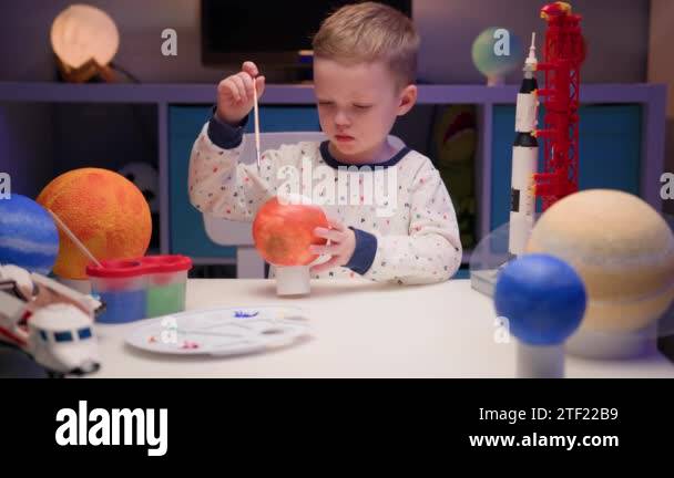 Blond boy paints planet solar system Mars with colorful paints sitting ...