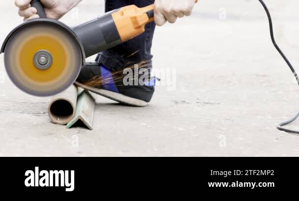 Foreman using angle grinder and cutting a metal tube. Artisan cuts ...