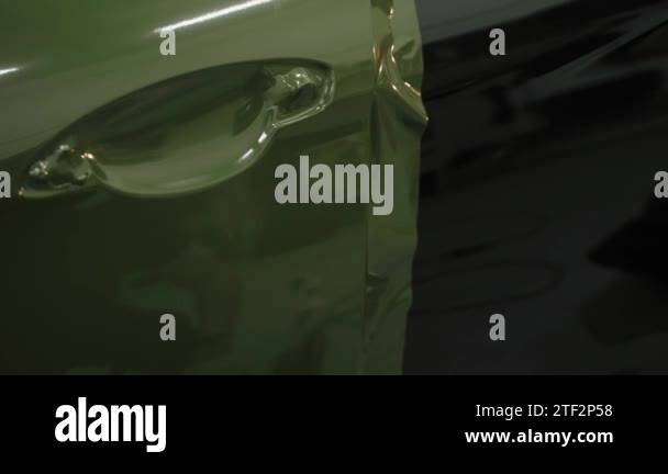 Close up shot of vinyl wrapping a car door. Dark green vinyl car wrap ...
