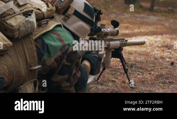 A bearded soldier lies on the forest litter in a tactical military ...