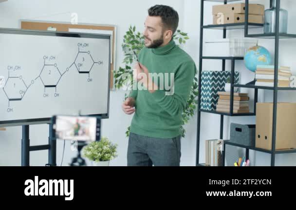Chemistry teacher recording video in class teaching online pointing at ...