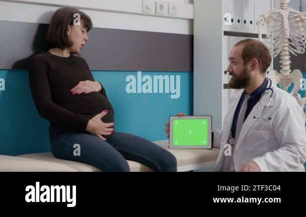 Patient with pregnancy belly and medic using horizontal greenscreen ...