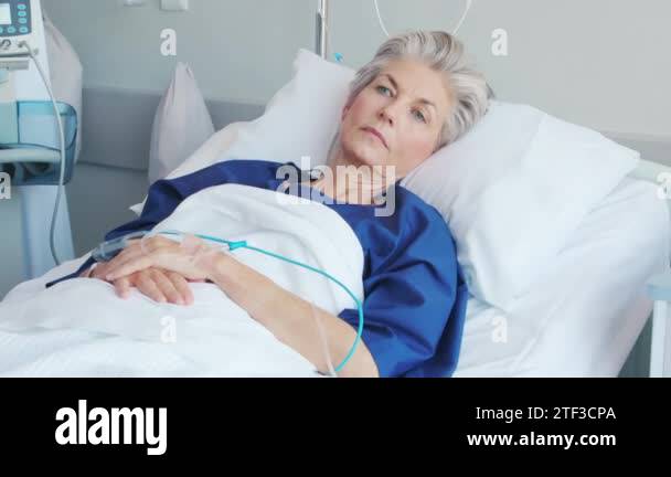 Mature woman recovering from illness while lying on hospital bed with ...