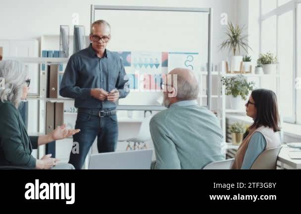 Middle-aged businessman explaining information on posters attached to ...