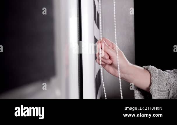 Woman hands pulling string as blinds drop window roller duo system day ...