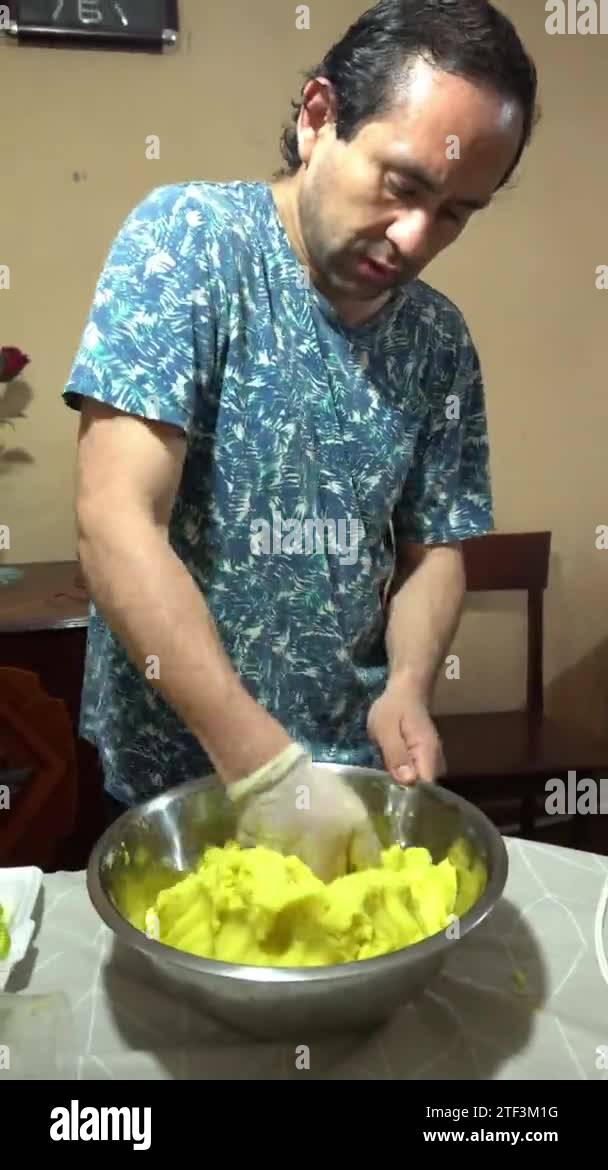 vertical video of a man kneading yellow potato with his hands in a ...
