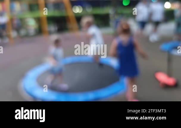 Children jump on a street trampoline in the park. Easily blurred ...