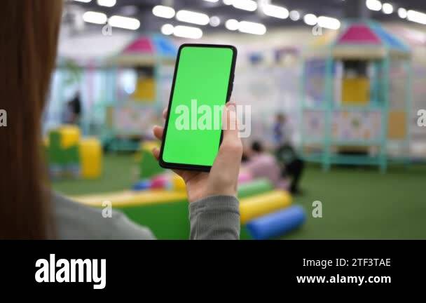 Young mother uses smartphone with green mock-up screen. Concept of ...