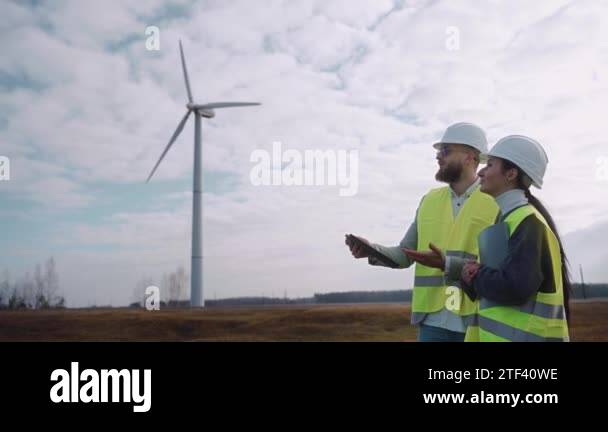 Ecological engineers use digital tablet and talk at the windmill field. Environmental engineers ...