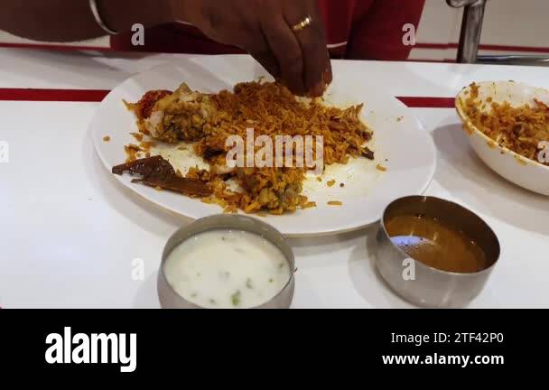 Man eating Indian popular food chicken biriyani served with curd and ...