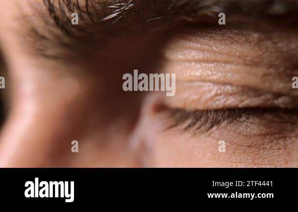 Close-up of brown eye blinking in Slow Motion, Young Man is opening and ...
