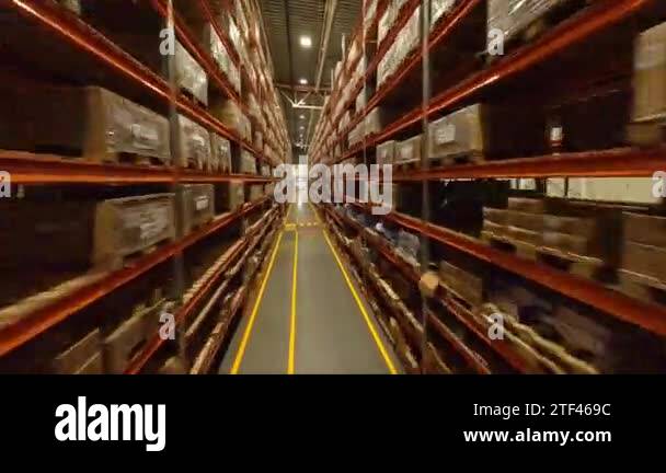 Motion through aisle between high racks with product boxes in ...