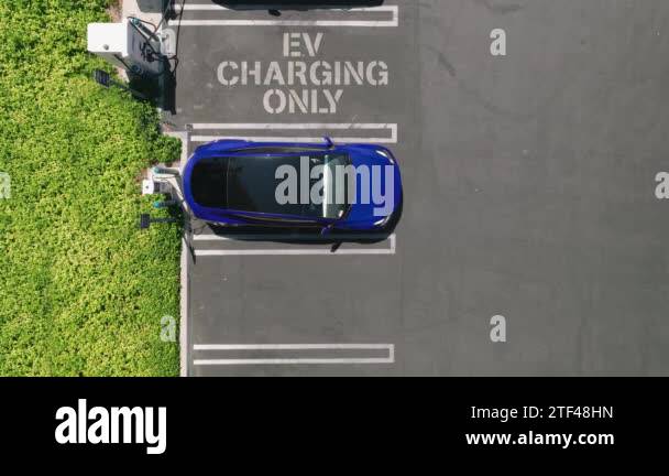Aerial view fully charged blue car leaving EV charging station in city ...