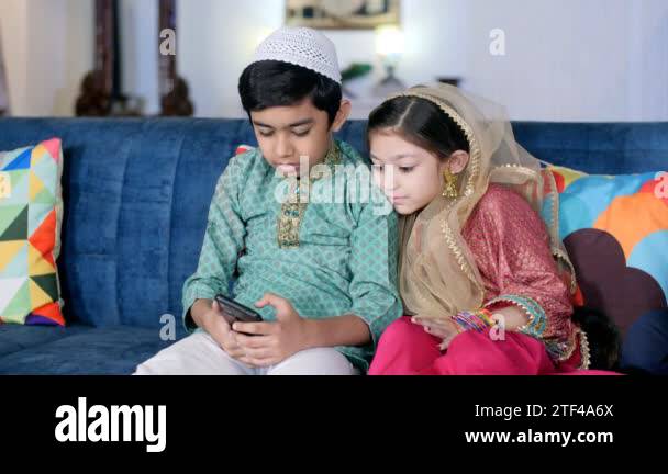 Two Muslim siblings busy using a mobile together at home - social media ...