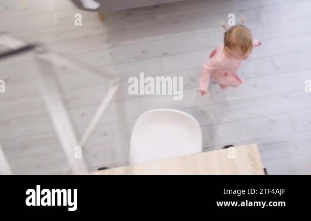 Little cute 2 years old girl having fun running around kitchen table ...