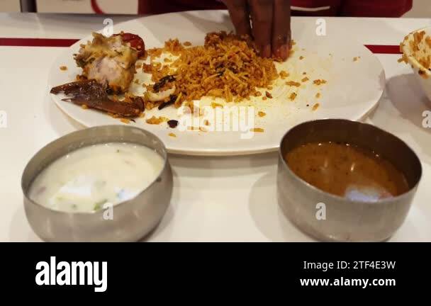 Man eating Indian popular food chicken biriyani served with curd and ...