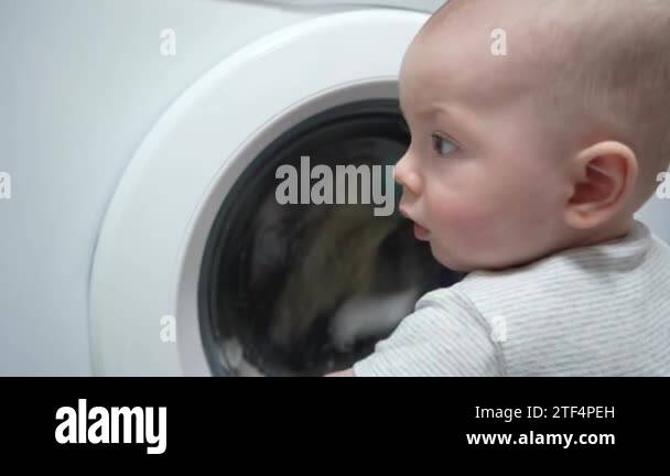 Cute little boy looks inside the washing machine. Child is looking into ...