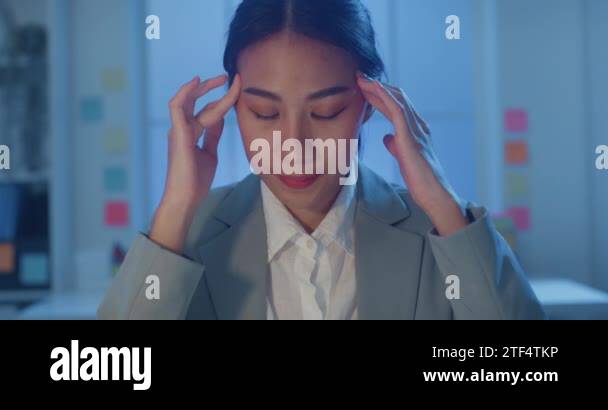 Young Asia businesswoman sit with laptop and tablet on desk rubbing eye ...