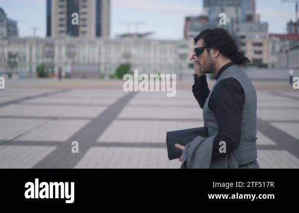 Live camera follows man walking on city square in slow motion looking ...