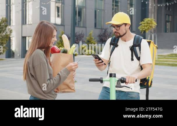 Woman meeting delivery man. Young woman collects a package of food from ...