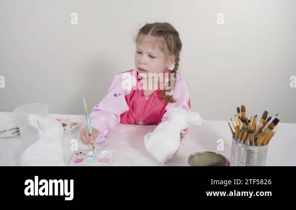 Little girl painting paper mache figurine at homeschooling art class ...