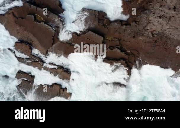Aerial birds eye overhead top down view of waves rolling over rock ...
