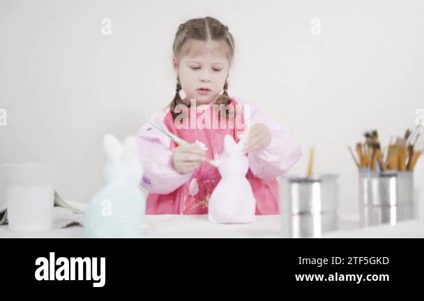Little girl painting paper mache figurine at homeschooling art class ...