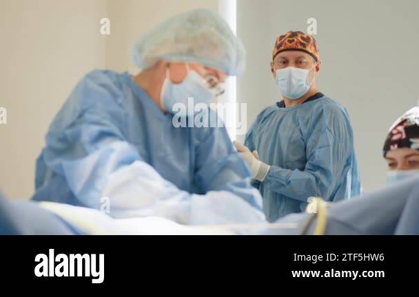 Surgeons team preforming operation in hospital operating theater, male ...