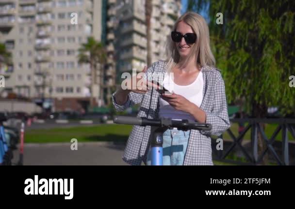 Blonde woman with black glasses uses app on her smartphone to unlock ...