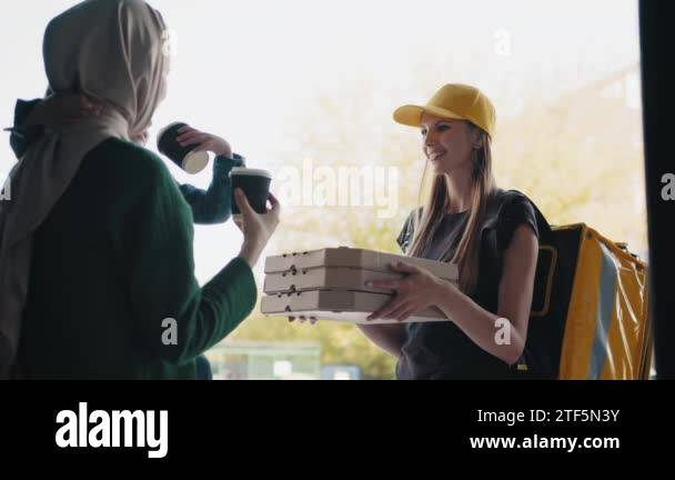 Food delivery. A cheerful courier brings boxes of pizza and drinks ...
