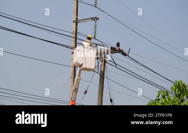 Electrician worker in lift bucket working on an electric pole to ...