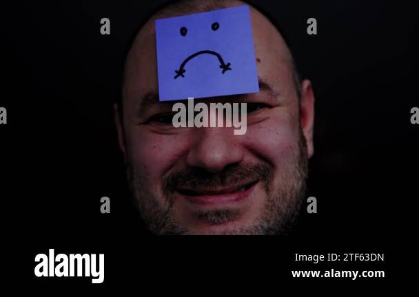 Sad man trying to smile with a sad smiley. Dark background. Depression ...