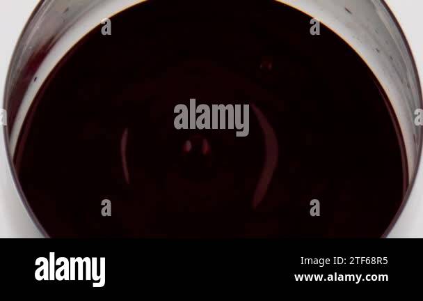 Red wine droplet falling glass closeup. Smooth liquid surface ripple in ...