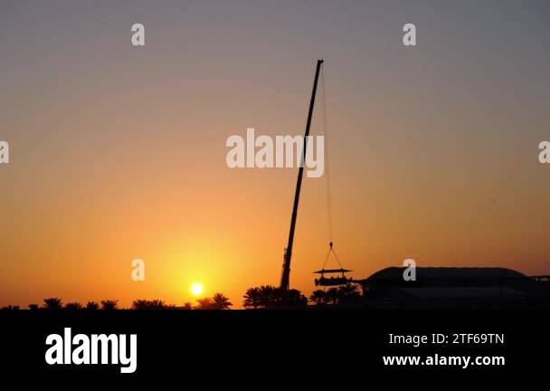 Crane keeps on hanging platform with dinning people alone the sunset ...
