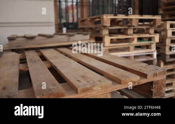 Wooden pallets stacked along a wall in a warehouse lot. Stacks of ...