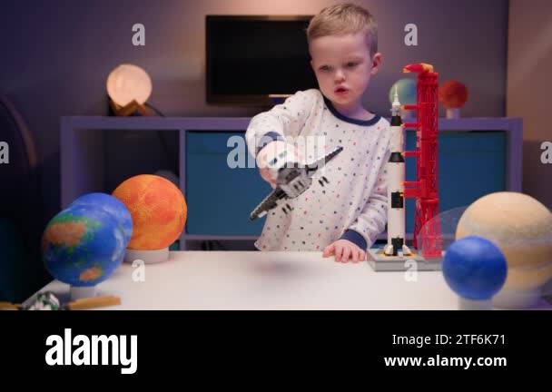 Little blonde boy kid plays with space shuttle from constructor, flies ...