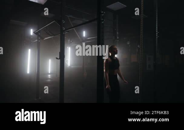 athletic woman is training on crossbar in gym, swaying and lifting legs ...