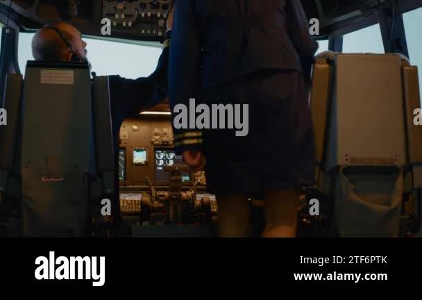Captain And Woman Copilot In Cockpit Preparing To Fly Airplane Using Dashboard Command Buttons