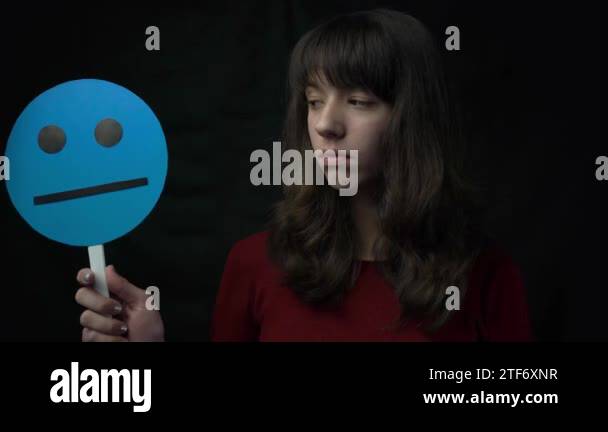 4k A human holds in his hand a mask with a emoticon with an unhappy ...