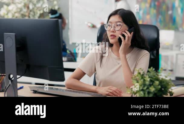 Young girl spends morning in front of computer in office taking care of chores speaks on phone ...