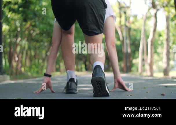 Back view of male athlete practicing at the park, starting sprinting ...