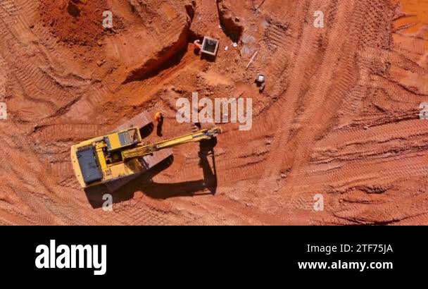 Excavator working at backhoe digs ground for laying concrete pipes on ...