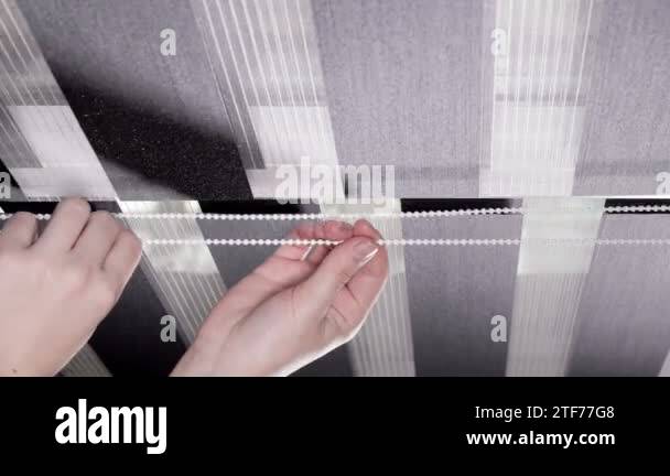 Woman hands pulling string as blinds drop window roller duo system day ...